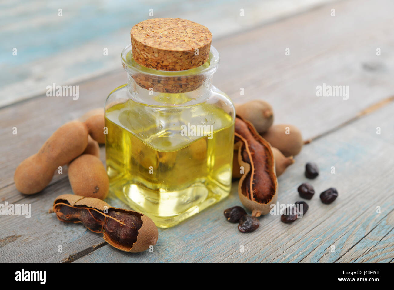 Essential tamarind oil with tamarind pods on old wooden background ...