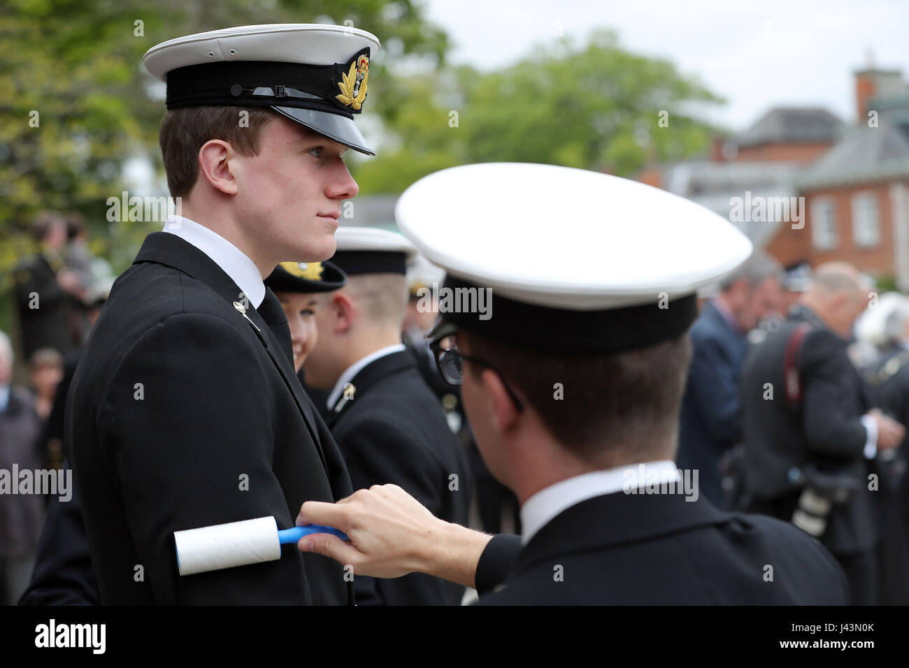 A cadet uses a lint brush to clean the uniform of a fellow cadet during ...