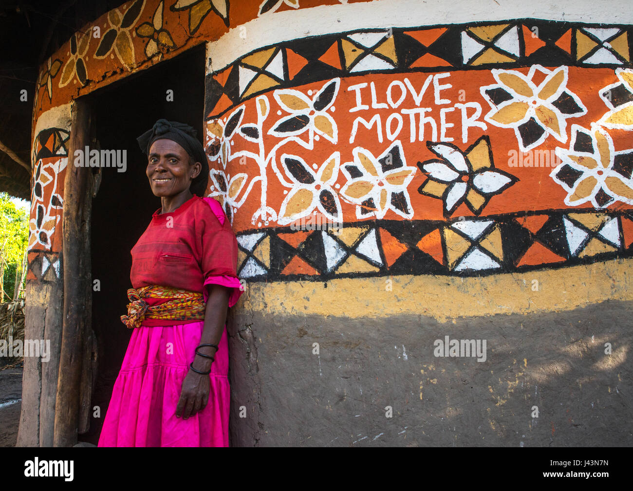 Ethiopian woman standing in front of her traditional painted house ...
