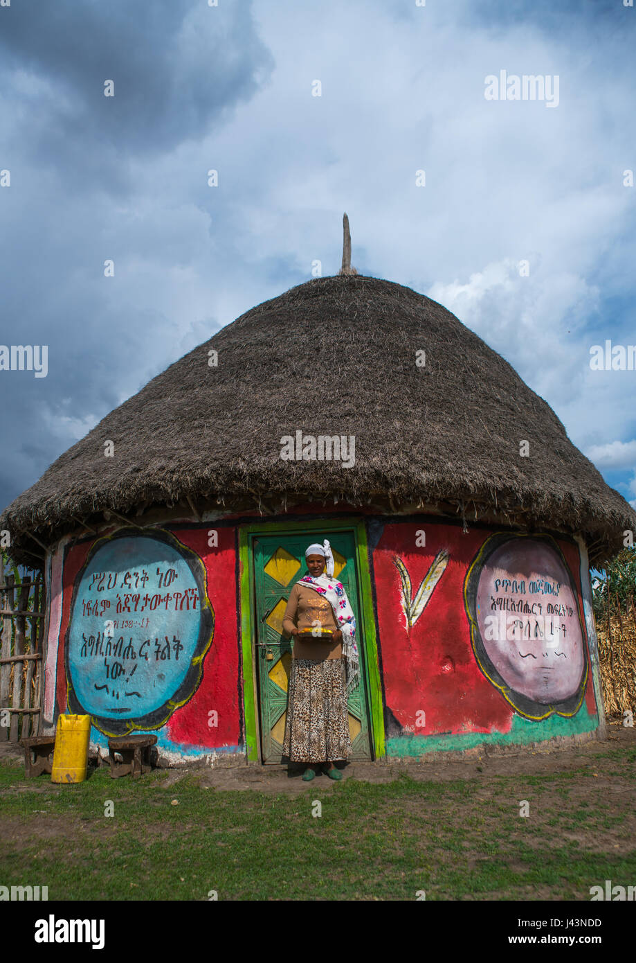 Ethiopian woman standing in front of her traditional painted house ...