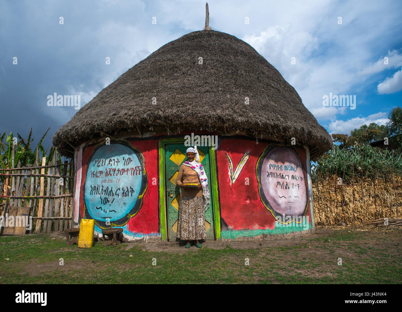 Ethiopian woman standing in front of her traditional painted house ...