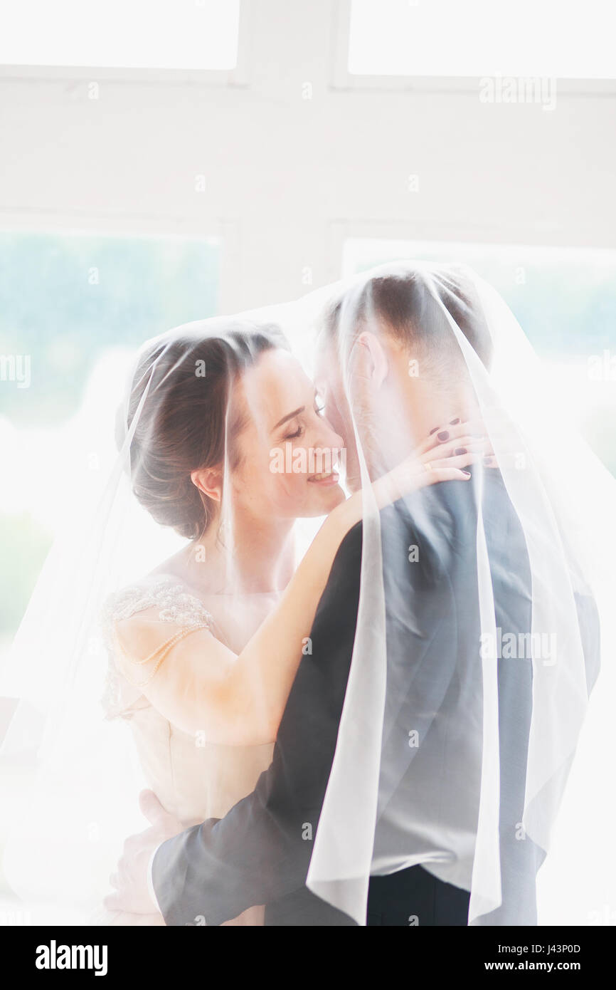 Wedding.Beautiful bride and groom portrait with veil over face. Stylish ...