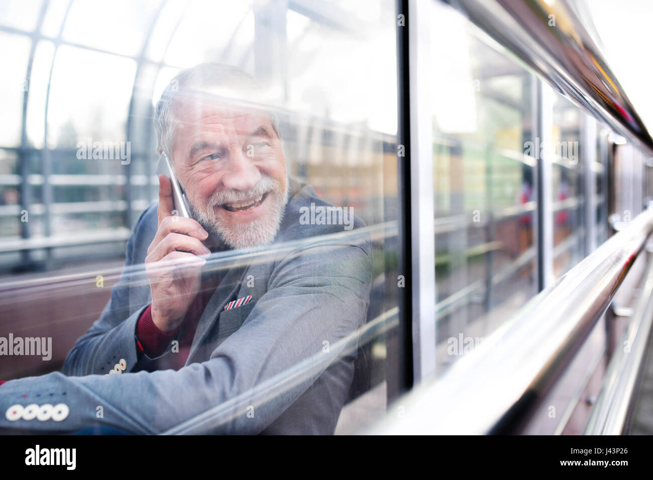 Senior man with smartphone in glass passage making phone call Stock ...