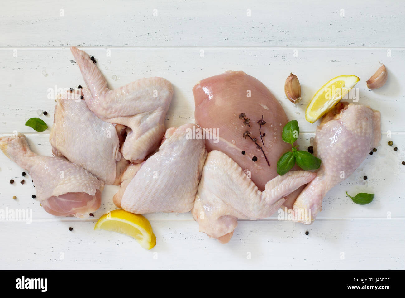 Fresh chicken meat raw fillet, wing, thigh and shank with lemon, spices ...