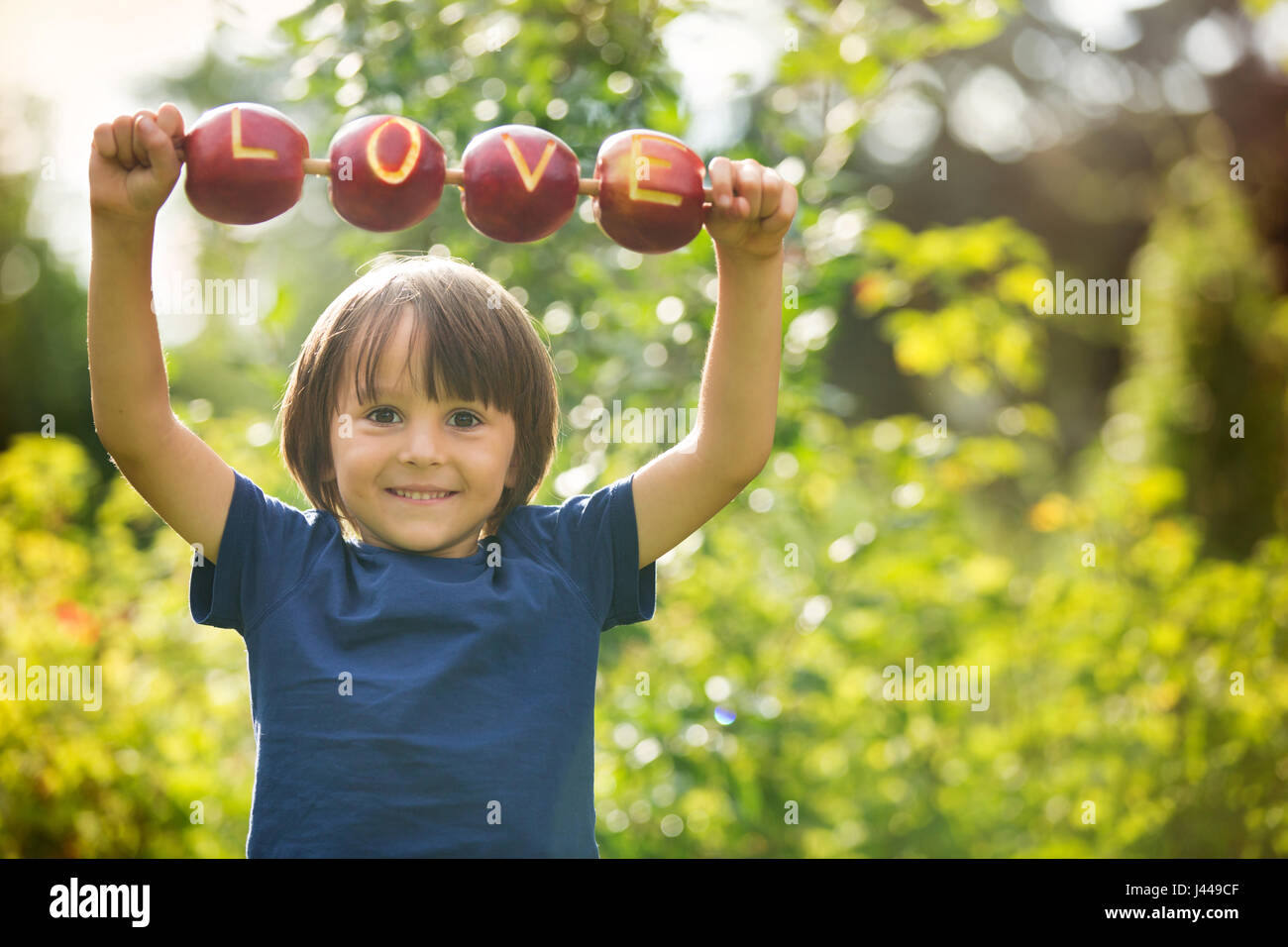 Cute little child, boy, holding a love sign, made from apples, letter ...