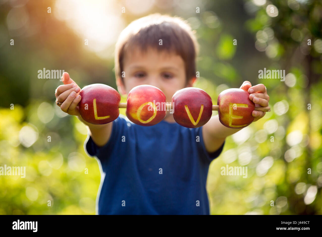 Cute little child, boy, holding a love sign, made from apples, letter ...