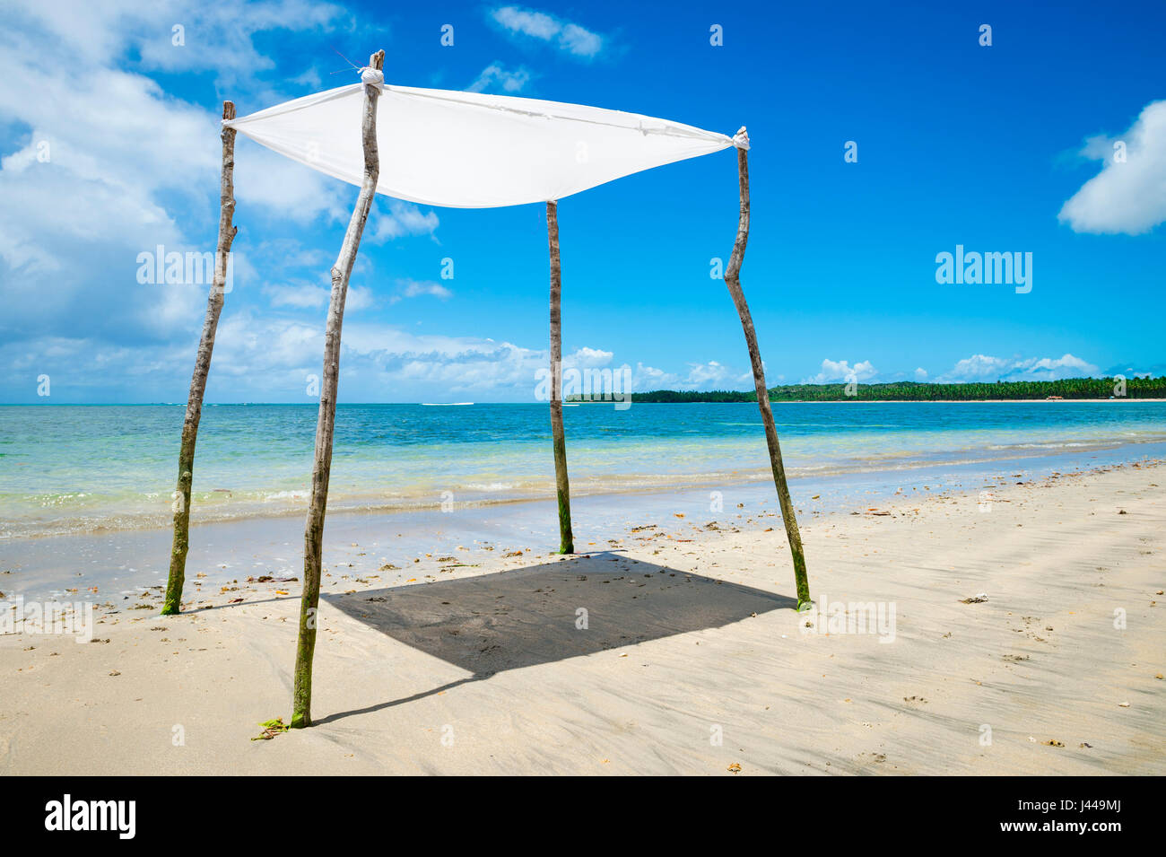 Rustic sun shade made from a sheet strung from sticks stands on an ...