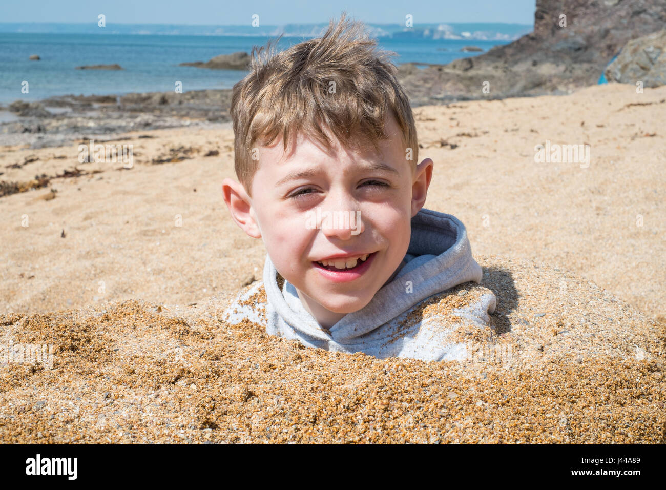 Seven year old boy playing in the sand at Hope Cove, Devon, England ...