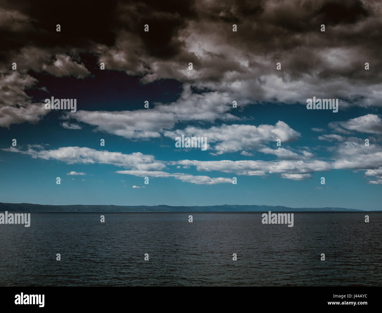 Rough clouds over calm sea with island at background Stock Photo - Alamy