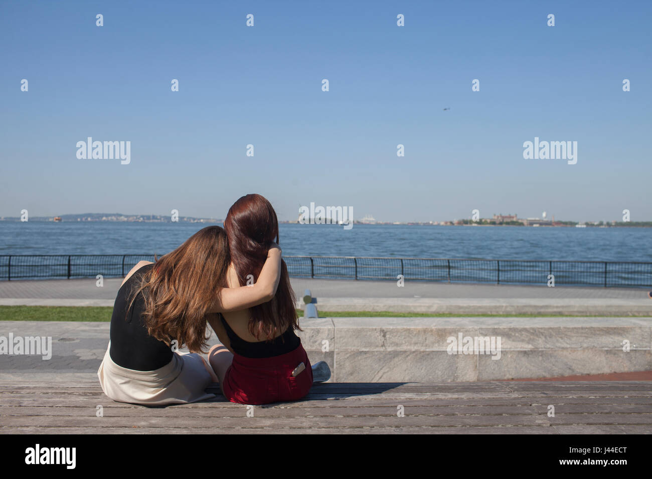 Back view of two young women sitting down Stock Photo - Alamy
