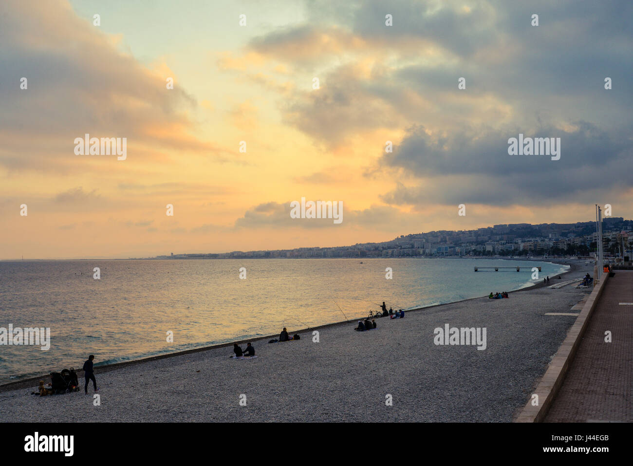 Peoples walking and relaxing on Nice beach at sunset Stock Photo - Alamy
