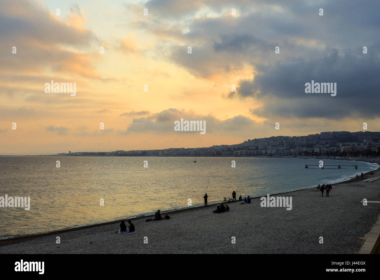 Peoples walking and relaxing on Nice beach at sunset Stock Photo - Alamy