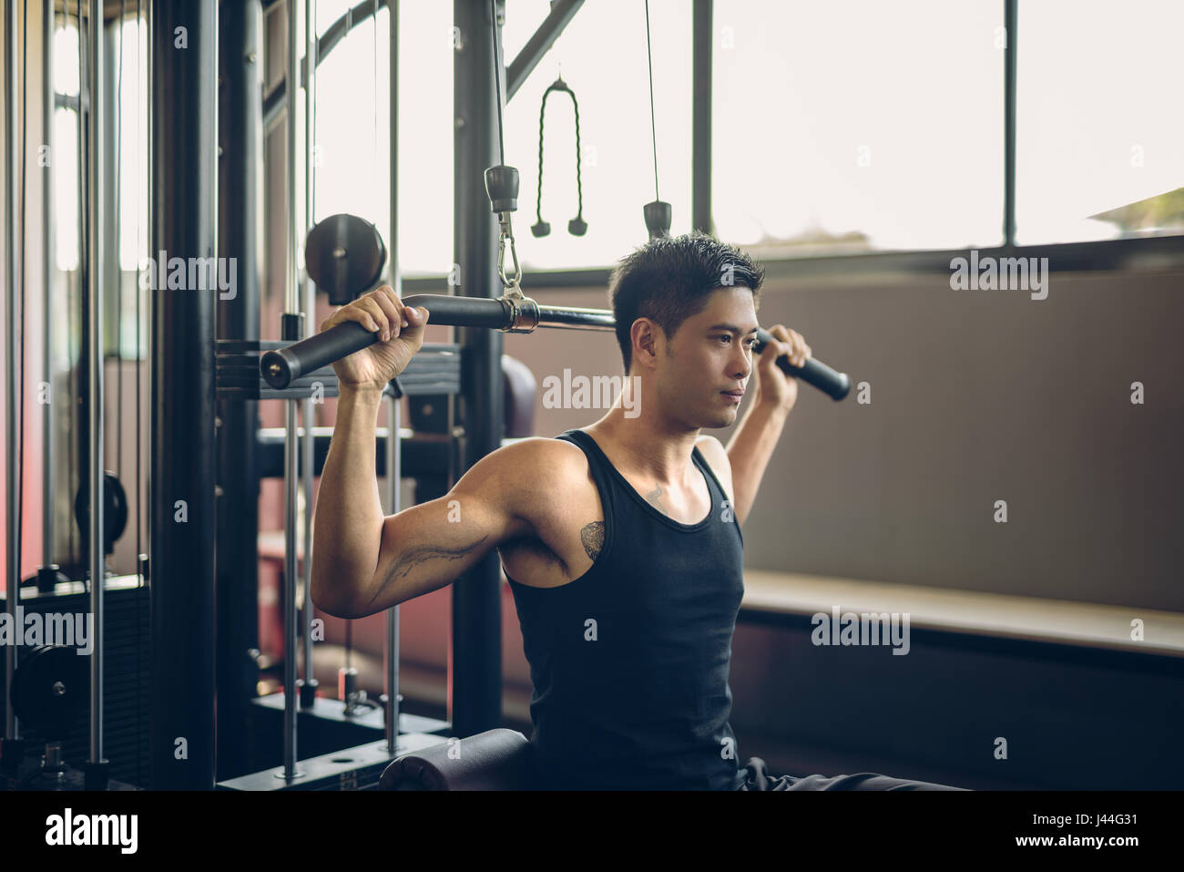 Asia Man with muscle in lat pull-down gym machine. Tough guy so strong ...