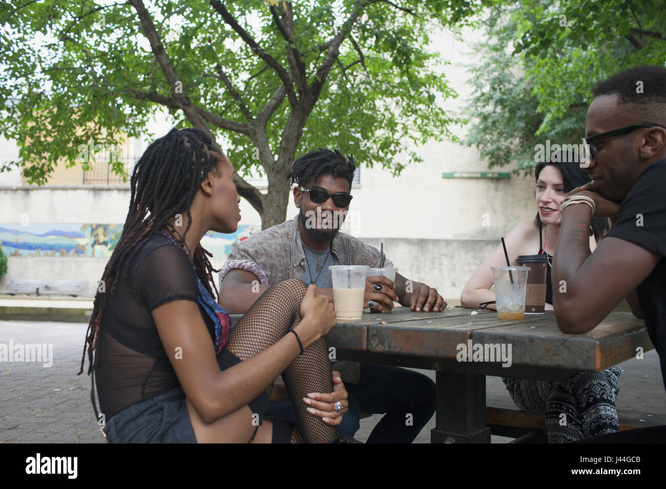 A group of friends having a conversation at a picnic table Stock Photo ...