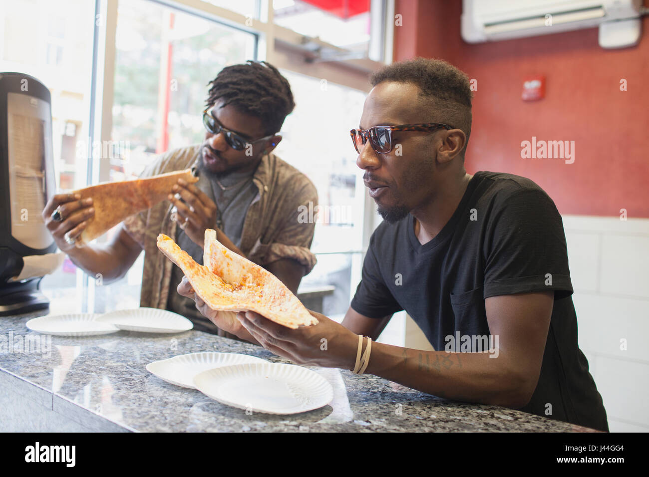 Two young men eating pizza Stock Photo - Alamy