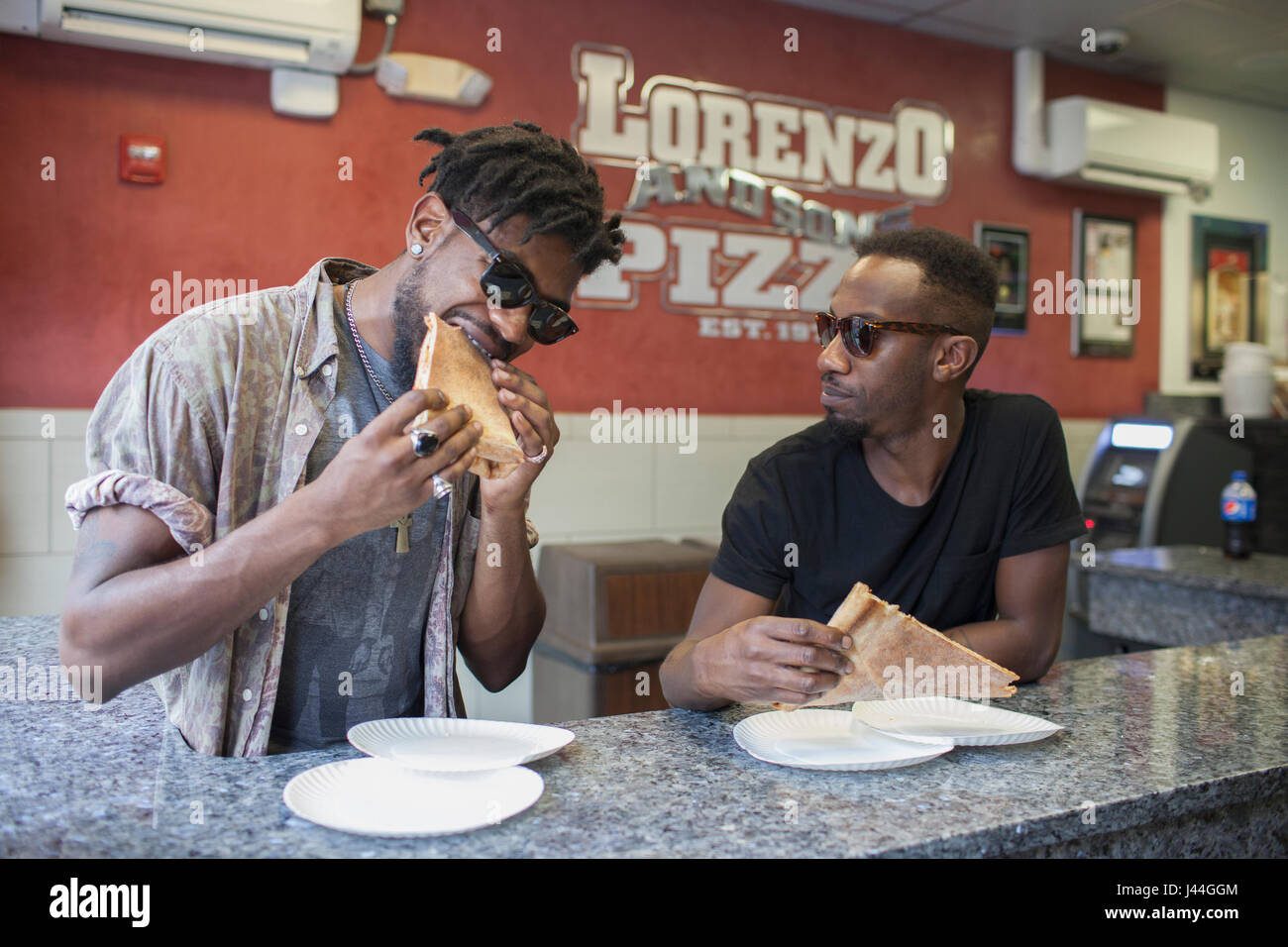 Two young men eating pizza Stock Photo - Alamy