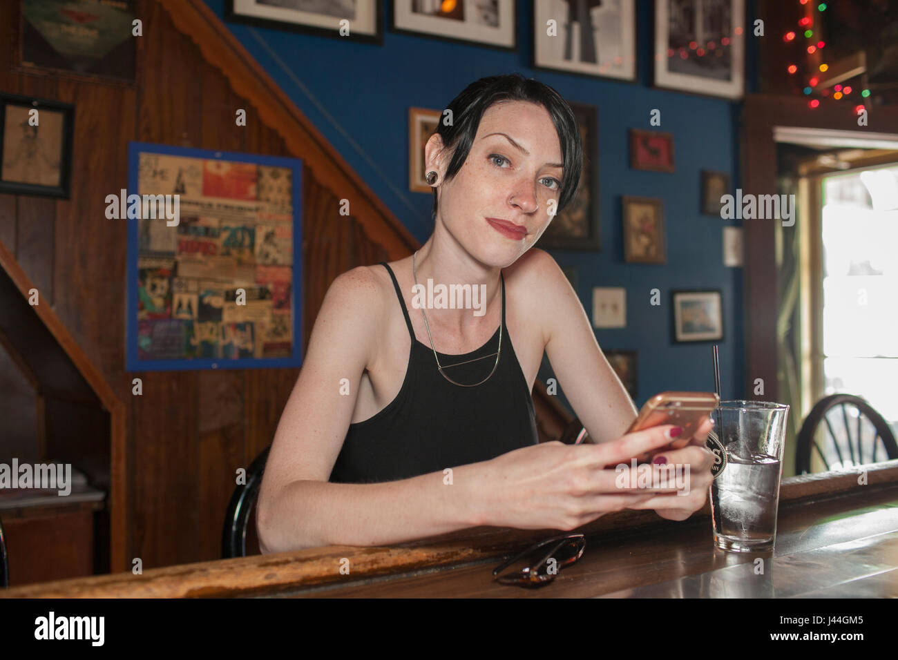 A young woman at a bar on her cell phone Stock Photo - Alamy