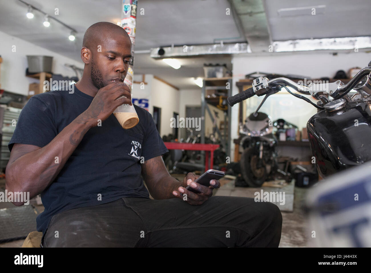 A young man drinking beside a motorcycle Stock Photo - Alamy