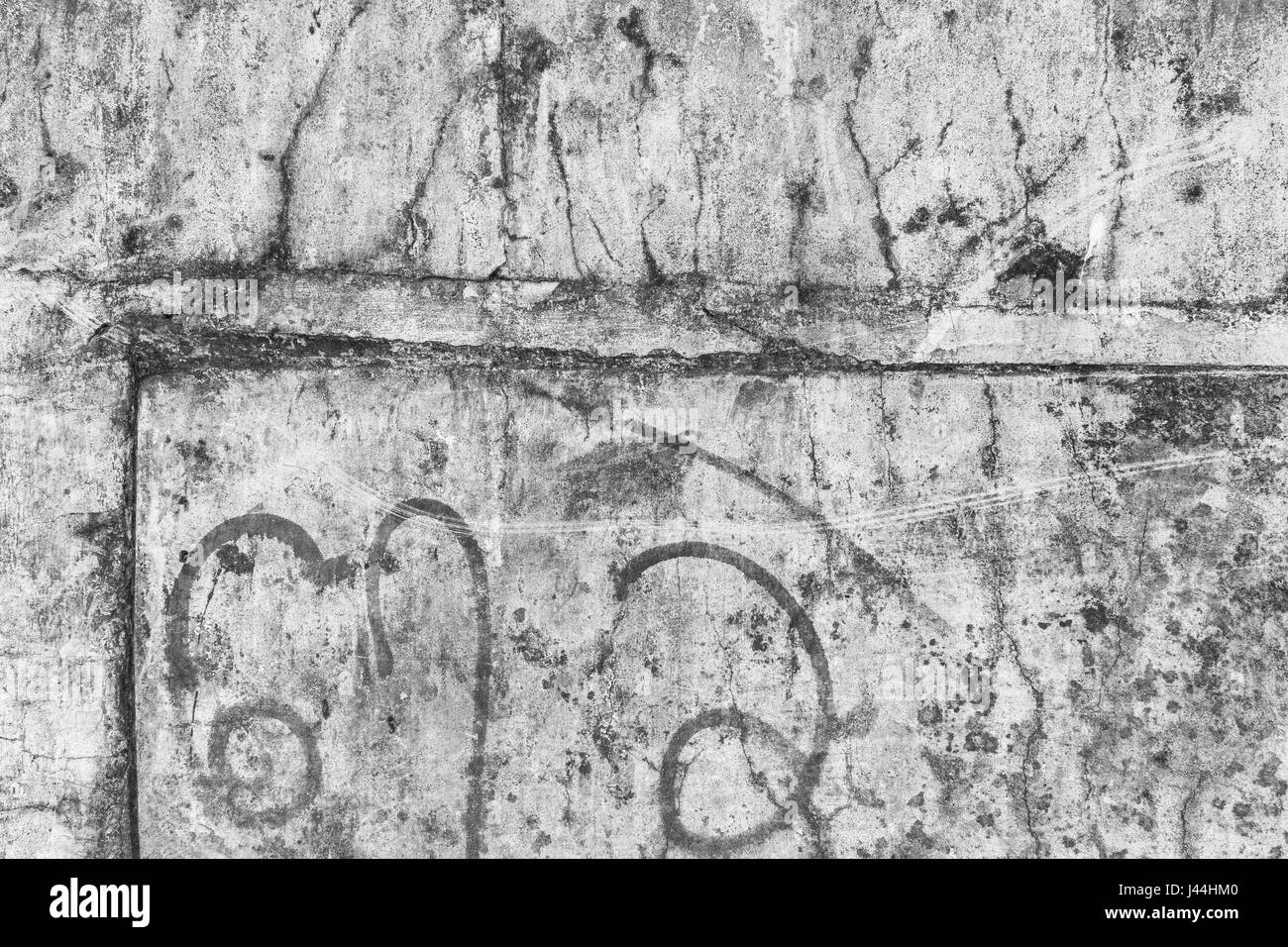 Weathered and aged grey concrete wall with some faded Burmese writing ...