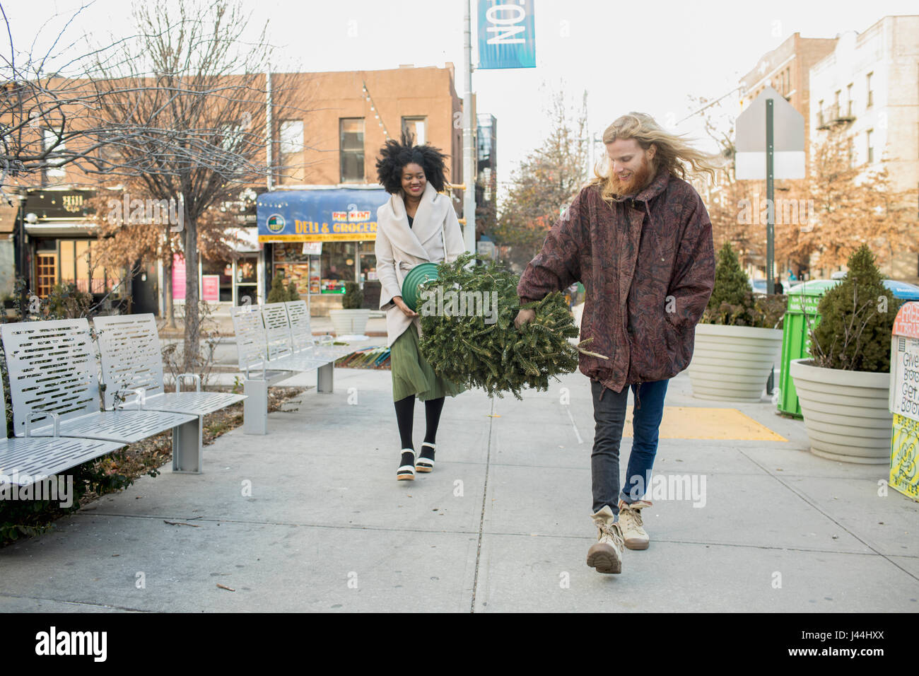 A young man and woman carrying a Christmas tree Stock Photo - Alamy