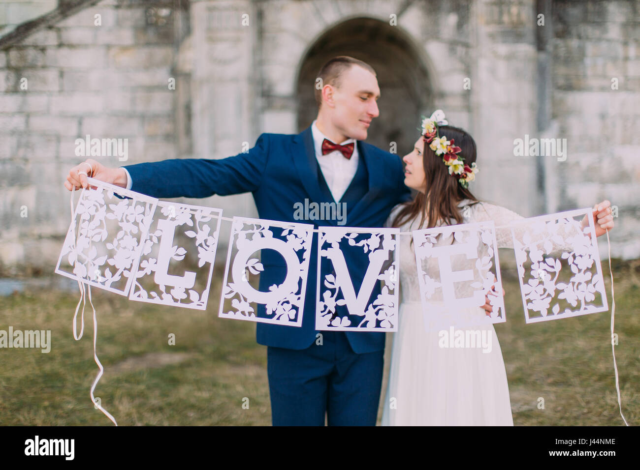 Happy just married bride and groom holding artistic papercut love ...