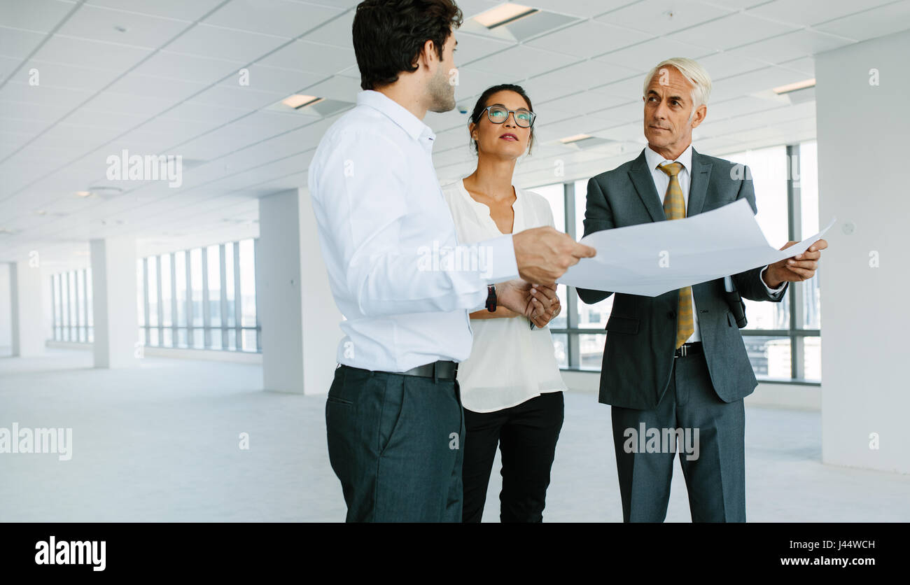 Business people and real estate agent discussing over blueprint of ...