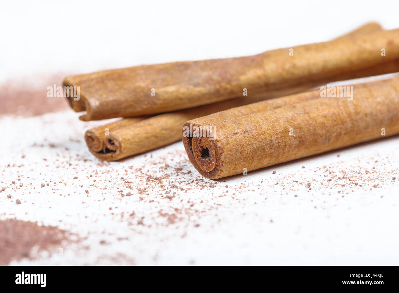 Cinamon sticks with cocoa powder, little spoon and herbs on white ...