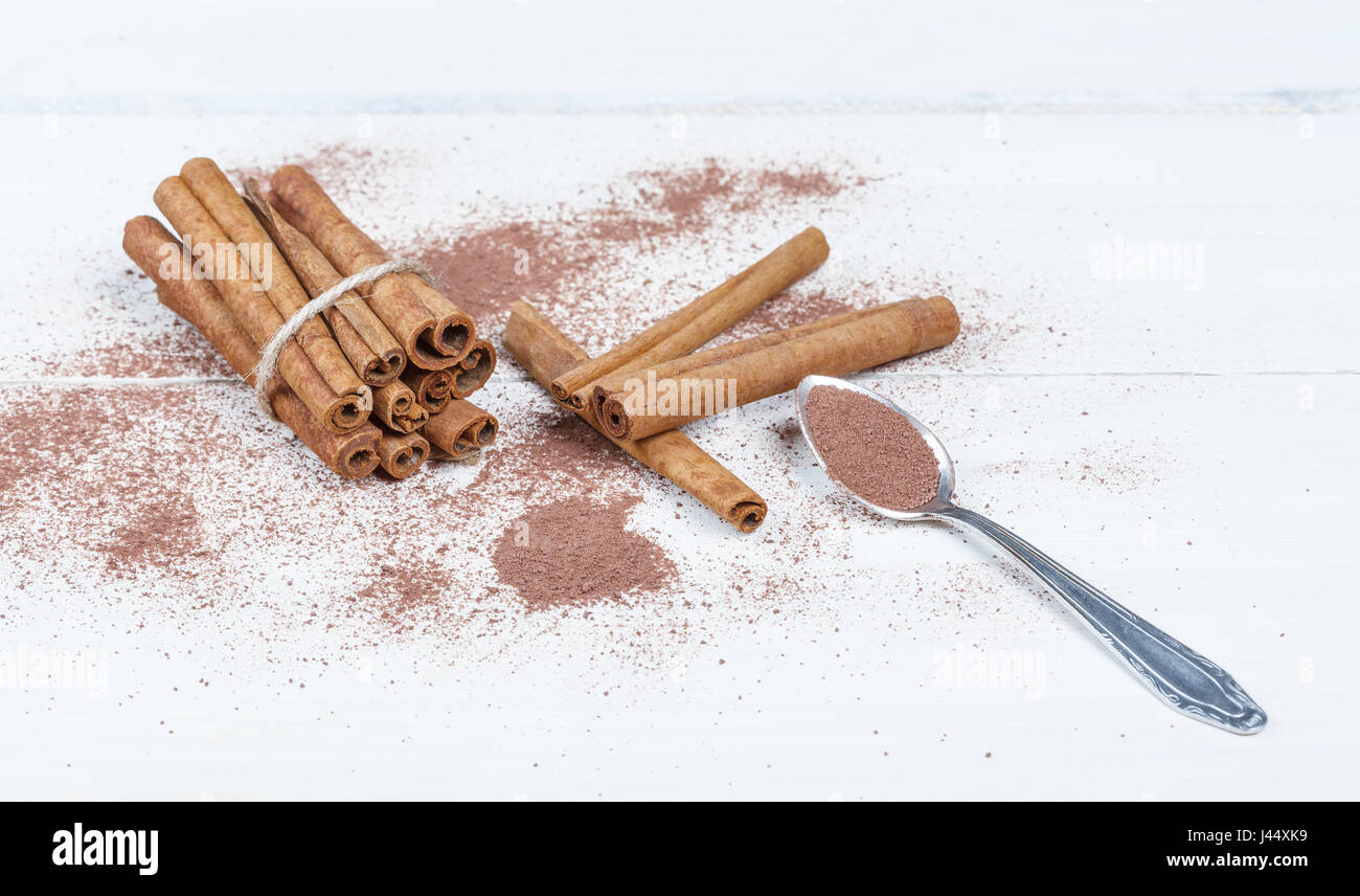 Cinamon sticks with cocoa powder, little spoon and herbs on white ...