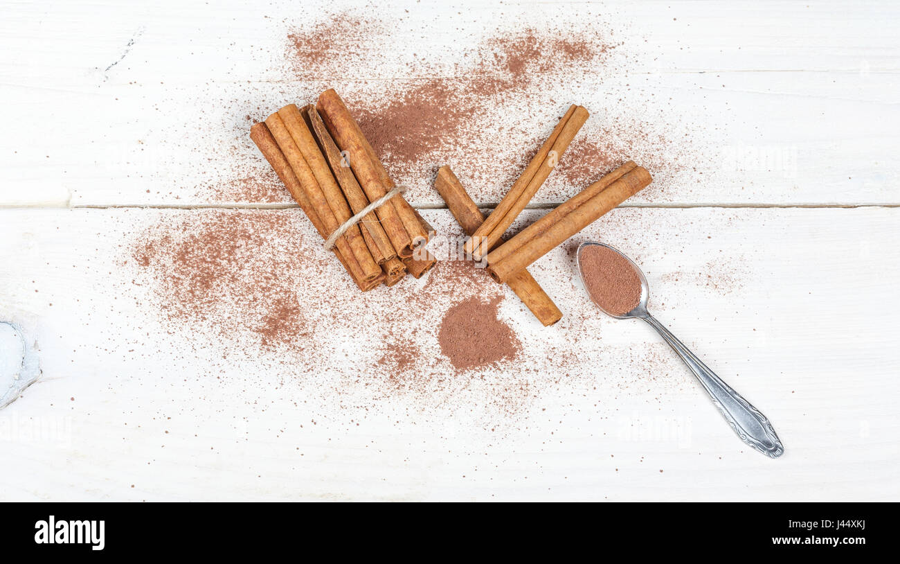 Cinamon sticks with cocoa powder, little spoon and herbs on white ...