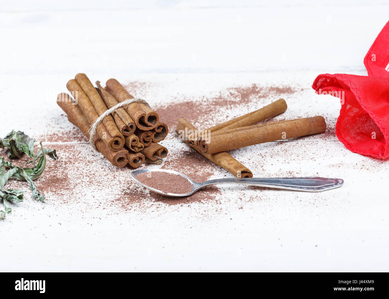 Cinamon sticks with cocoa powder, little spoon and herbs on white ...