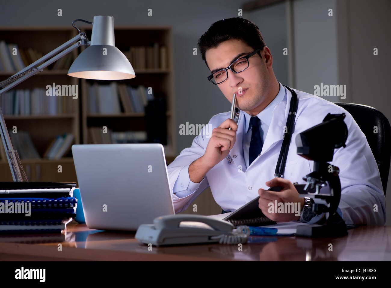 Young doctor working late in the office Stock Photo - Alamy