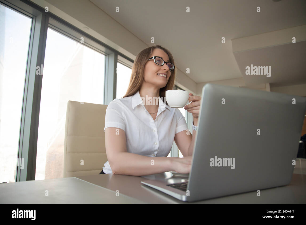Businesswoman drinking coffee at the office desk Stock Photo - Alamy