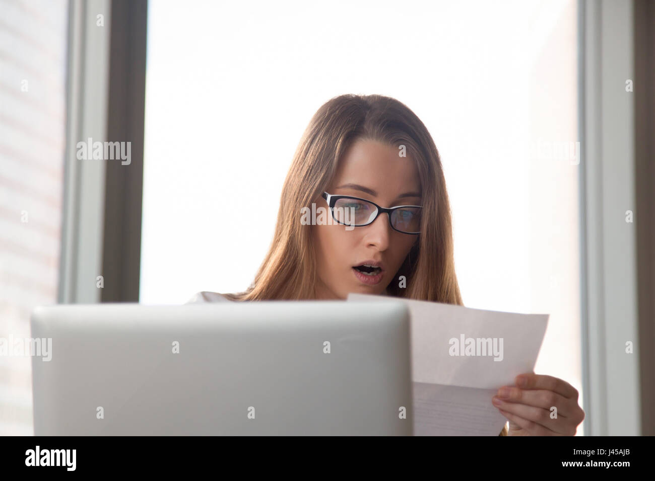 Surprised young businesswoman reading letter Stock Photo - Alamy
