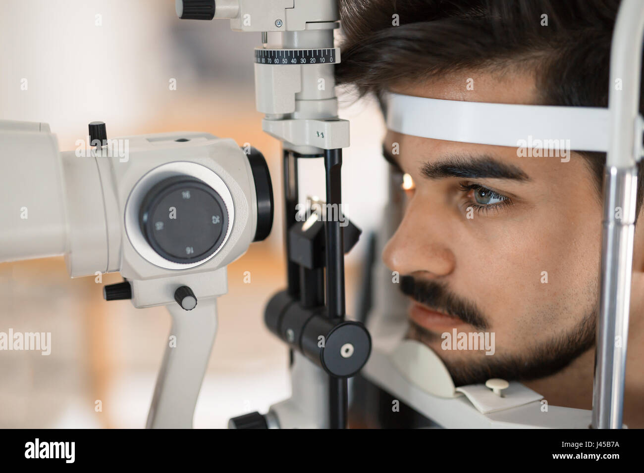 Patient or customer at slit lamp at optometrist or optician examining ...
