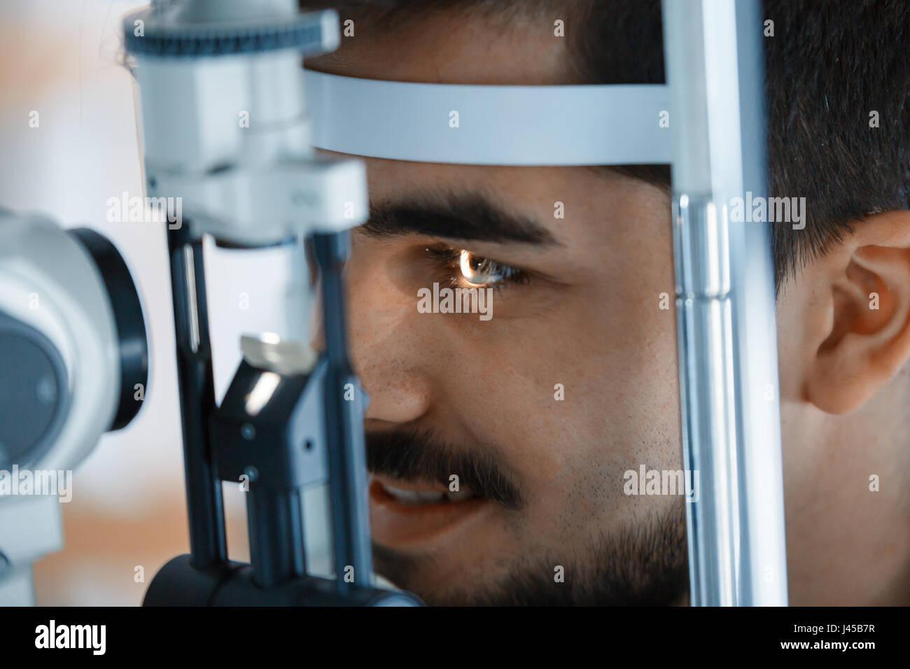 Patient or customer at slit lamp at optometrist or optician examining ...