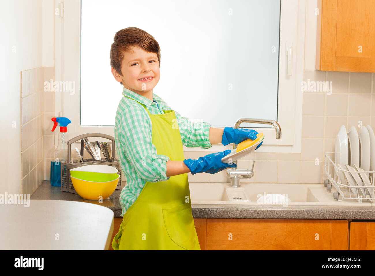 Boy in rubber gloves washing plates with sponge Stock Photo - Alamy