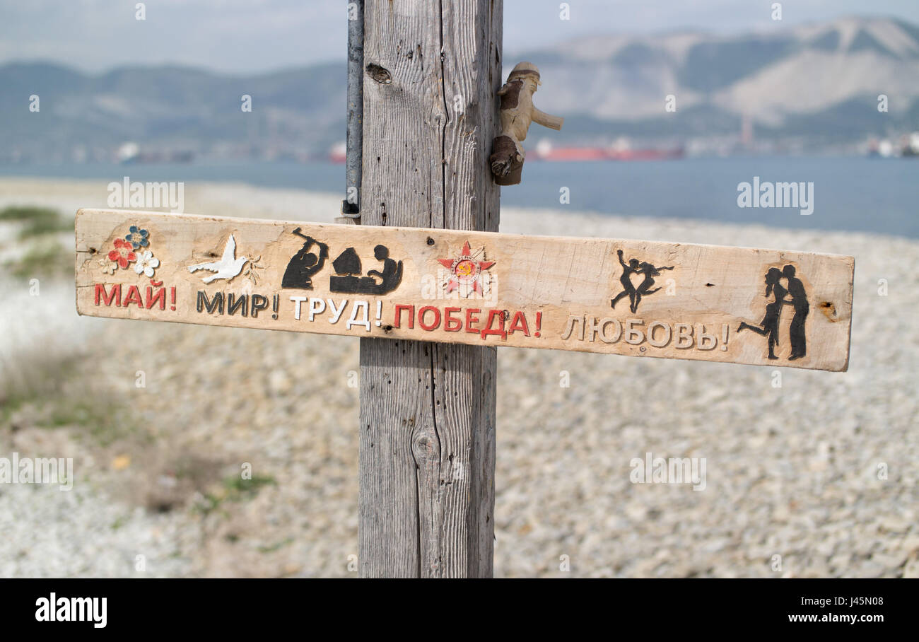 Wooden signboard in Russian on the background of the sea: May, Peace ...