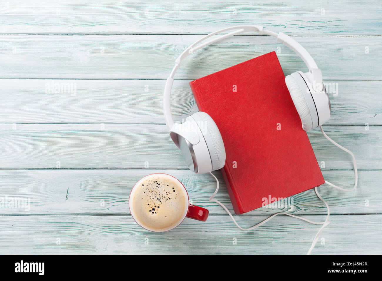 Audio book concept. Headphones, coffee and old book over wooden table ...
