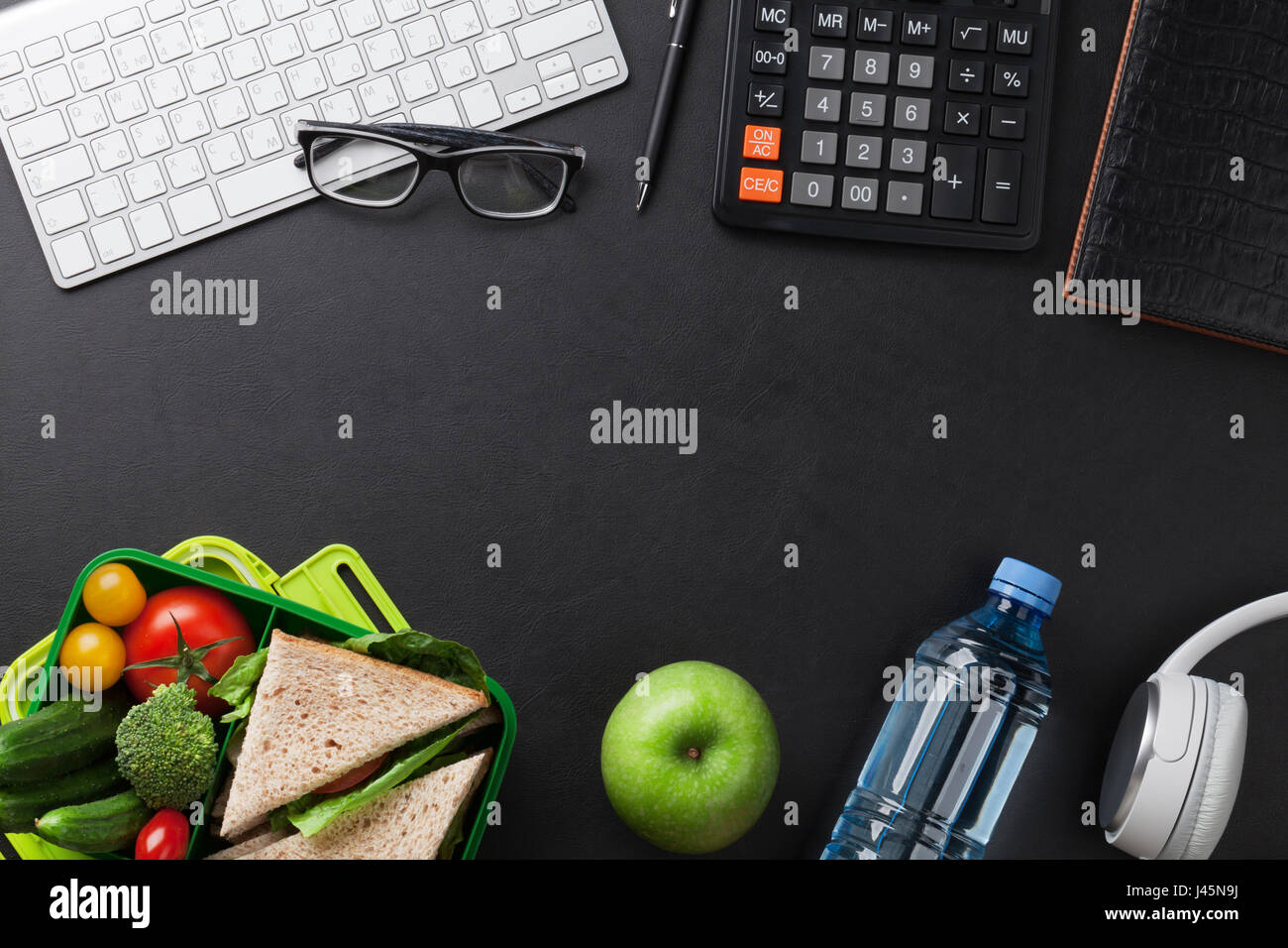 Office desk with supplies and lunch box with vegetables and sandwich ...