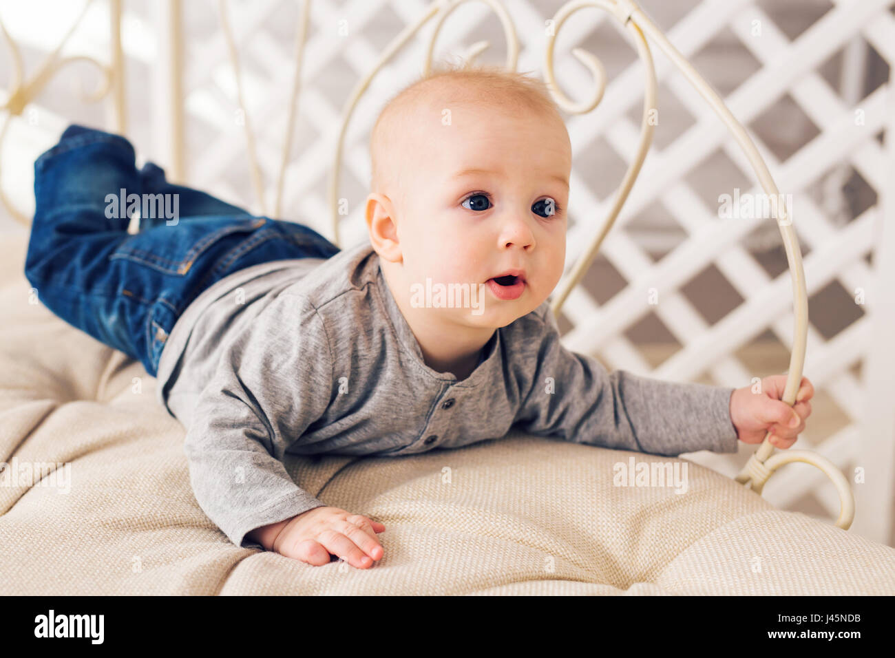 Adorable laughing baby boy in sunny bedroom. Newborn child relaxing ...