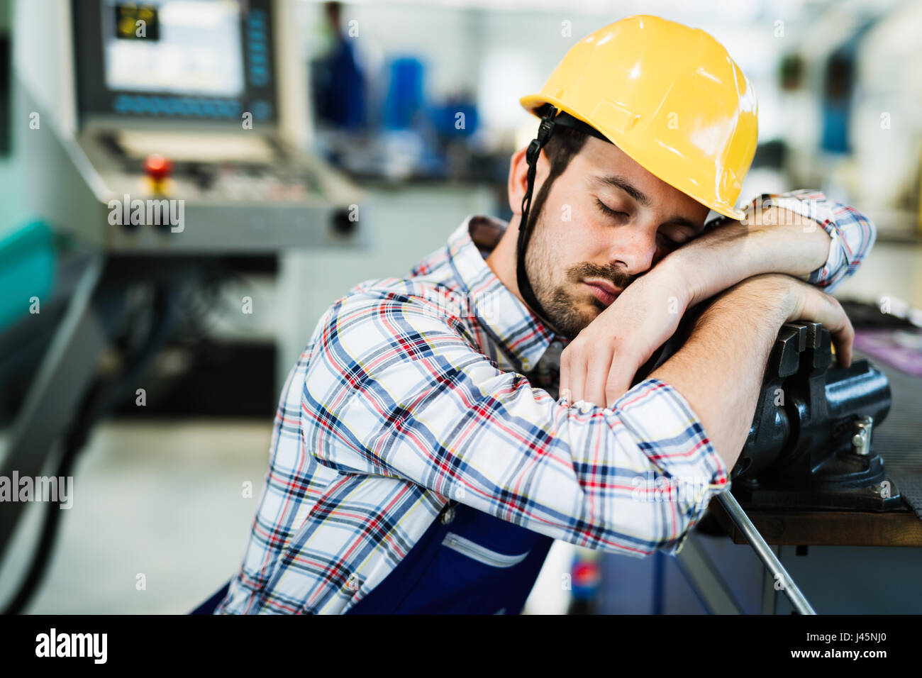 Tired overworked worker falls asleep during working hours in factory ...