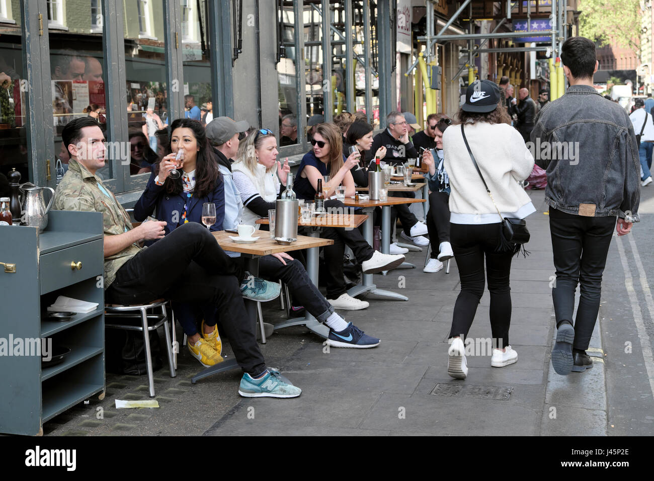 People drinking wine and beer sitting at tables outside a pub ...