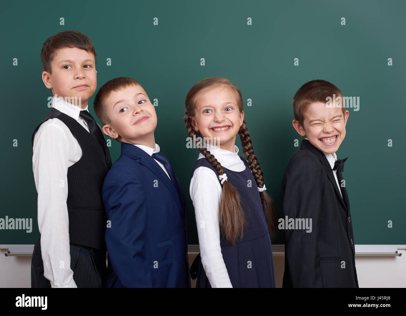 elementary school boy near blank chalkboard background, dressed in ...