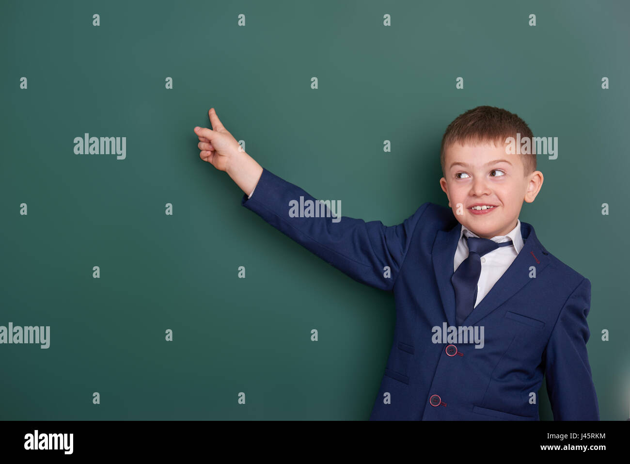 school boy point the finger near blank chalkboard background, dressed ...