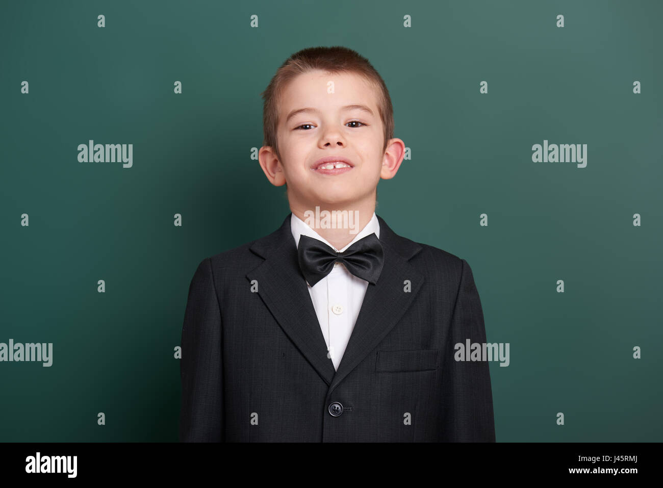 school boy portrait near green blank chalkboard background, dressed in ...