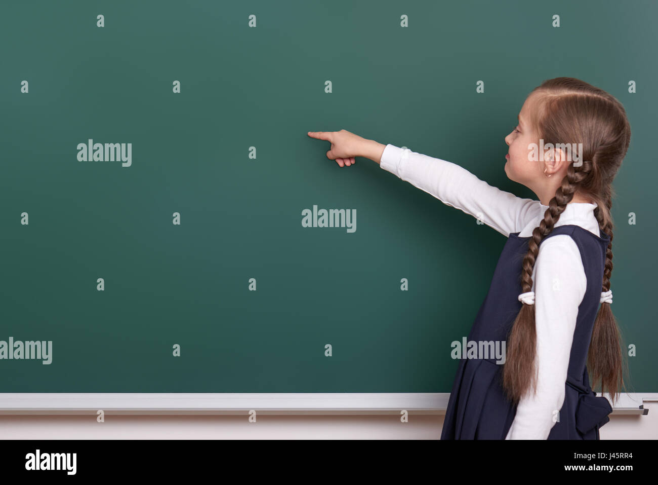school girl point the finger near blank chalkboard background, dressed ...