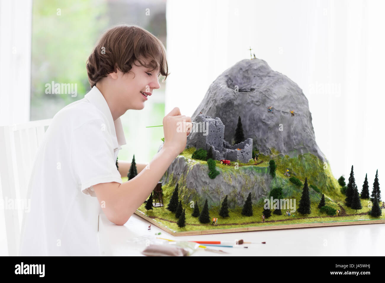 Teenager working on model building school project. Kids build miniature ...