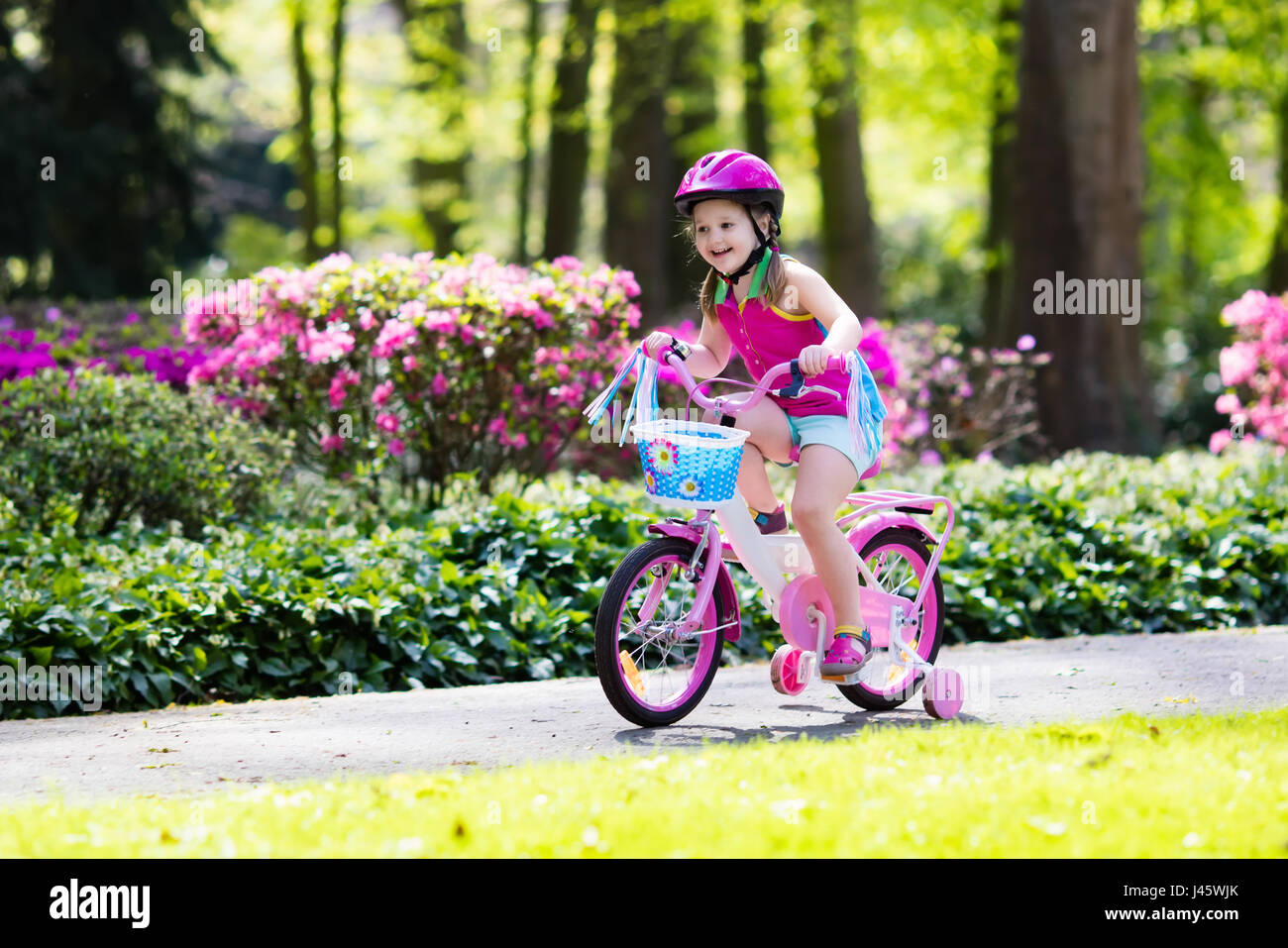 Child riding bike. Kid on bicycle in sunny park. Little girl enjoying ...