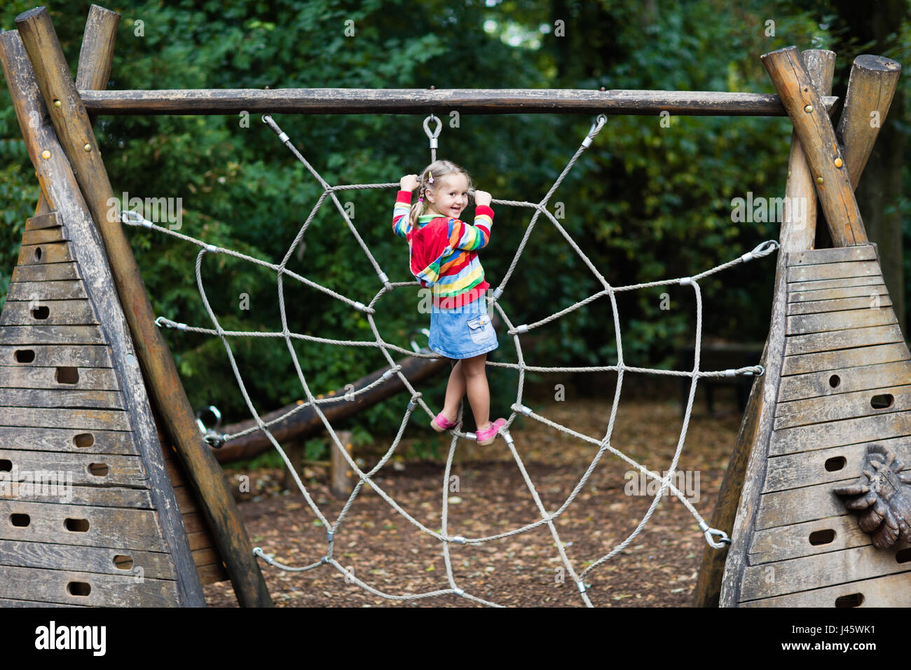 Active little child playing on climbing net and jumping on trampoline ...