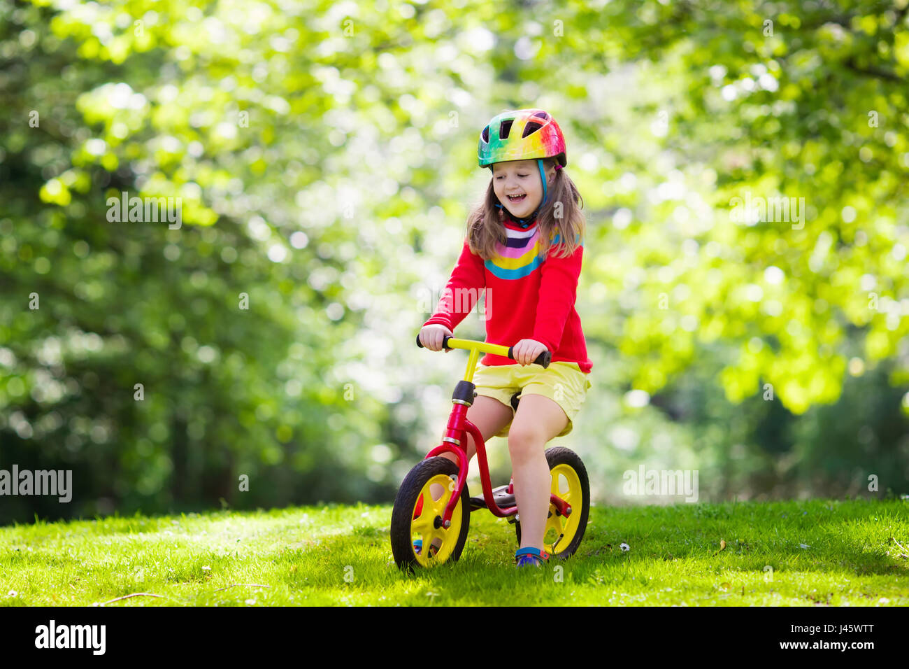 Child riding balance bike. Kids on bicycle in sunny park. Little girl ...